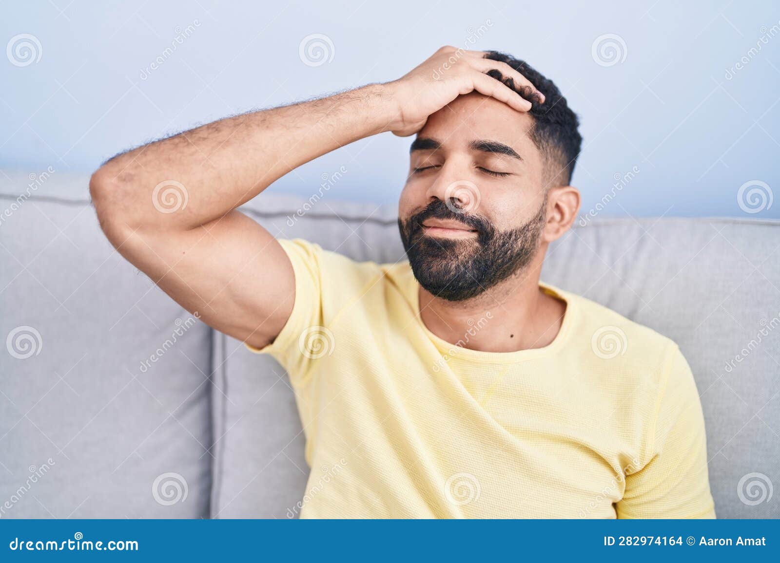 Young Arab Man Relaxed with Hand on Head Sitting on Sofa at Home Stock ...