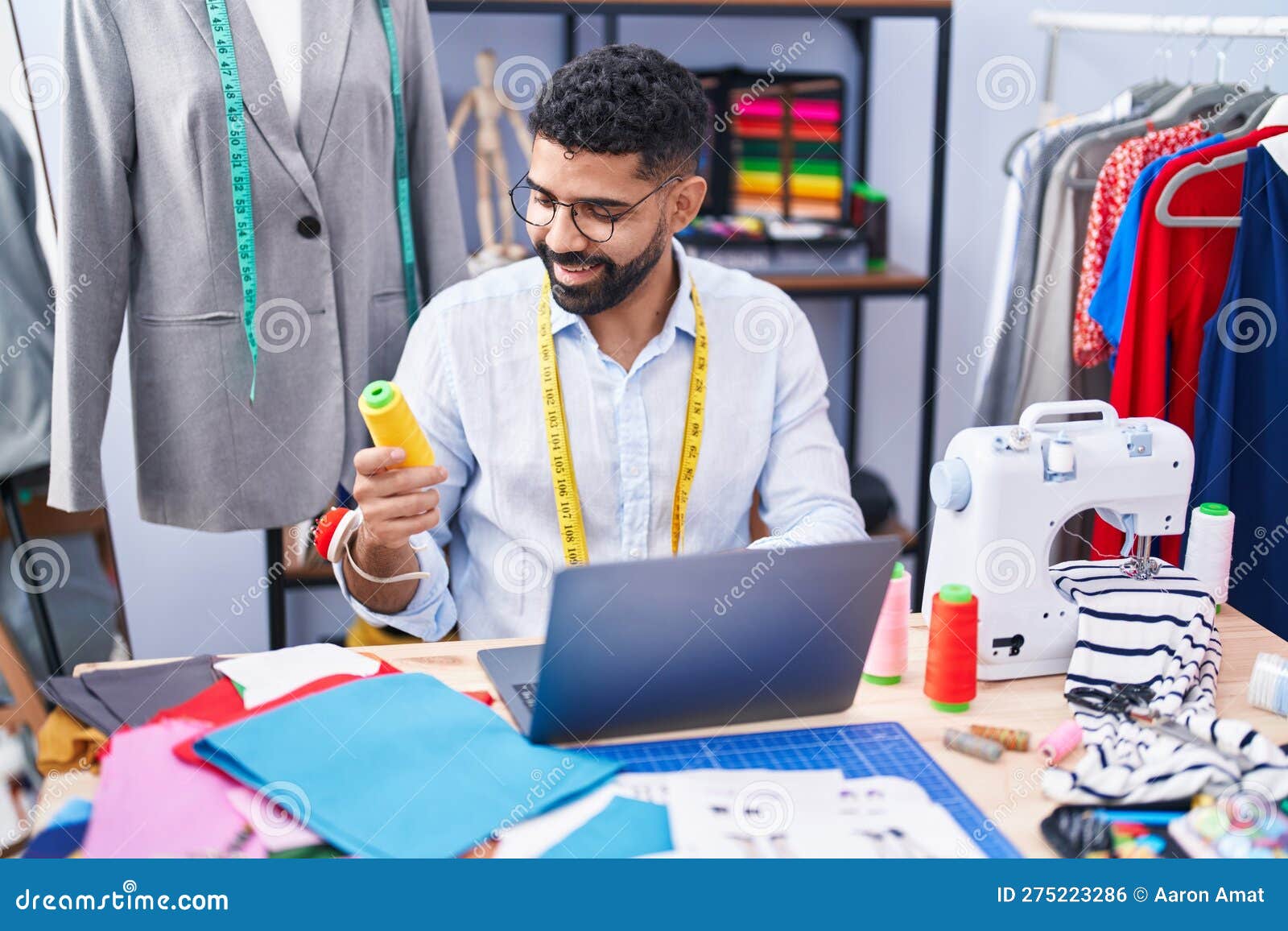 Young Arab Man Tailor Using Laptop Holding Thread at Tailor Shop Stock ...
