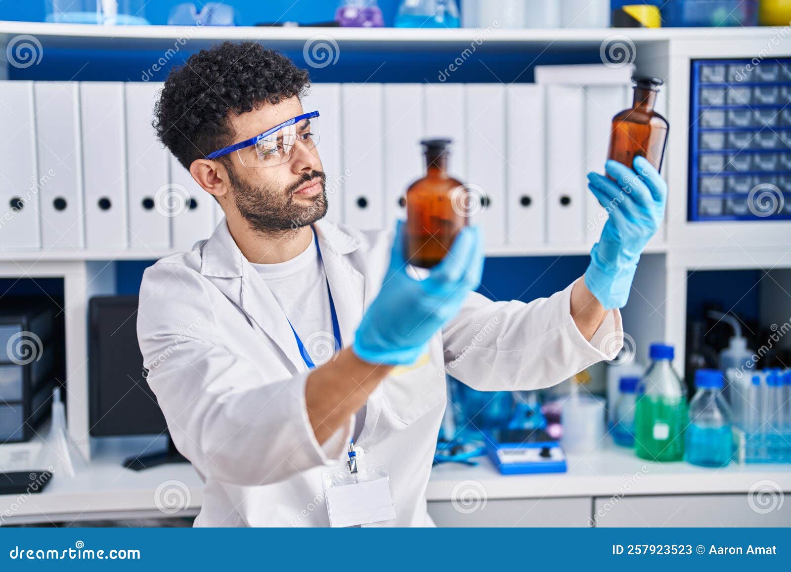 Young Arab Man Wearing Scientist Uniform Holding Bottles at Laboratory ...