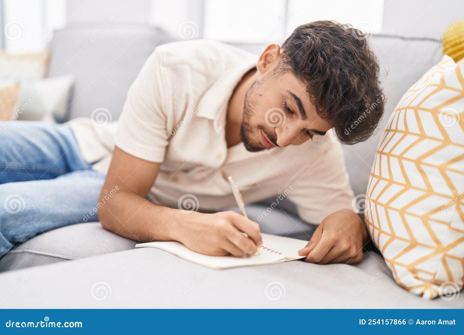 Young Arab Man Writing on Notebook Sitting on Sofa at Home Stock Photo ...