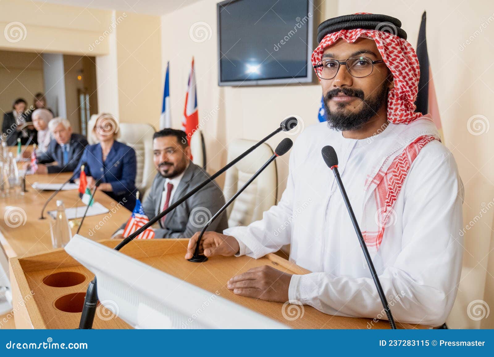 Young Arabian Speaker Looking at Camera while Standing by Tribune Stock ...