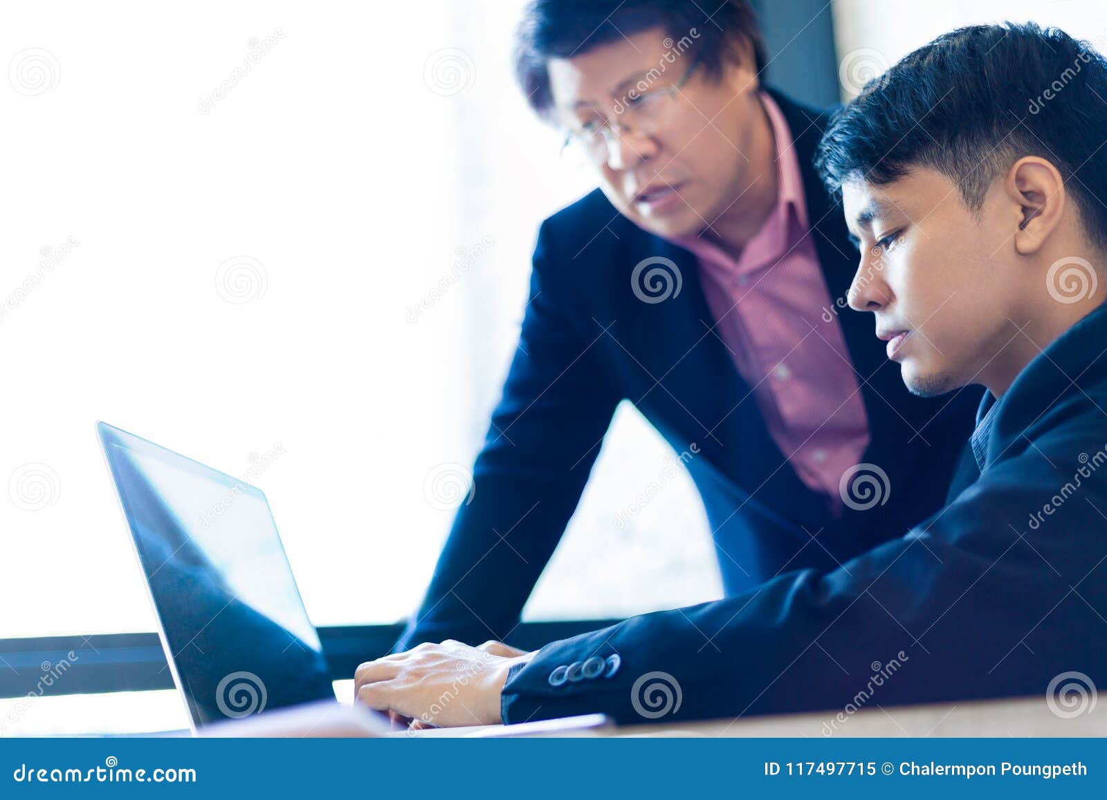 Young Asian Businessman Working on His Computer with His Business ... Young Asian Businessman Working on His Computer with His Business ...