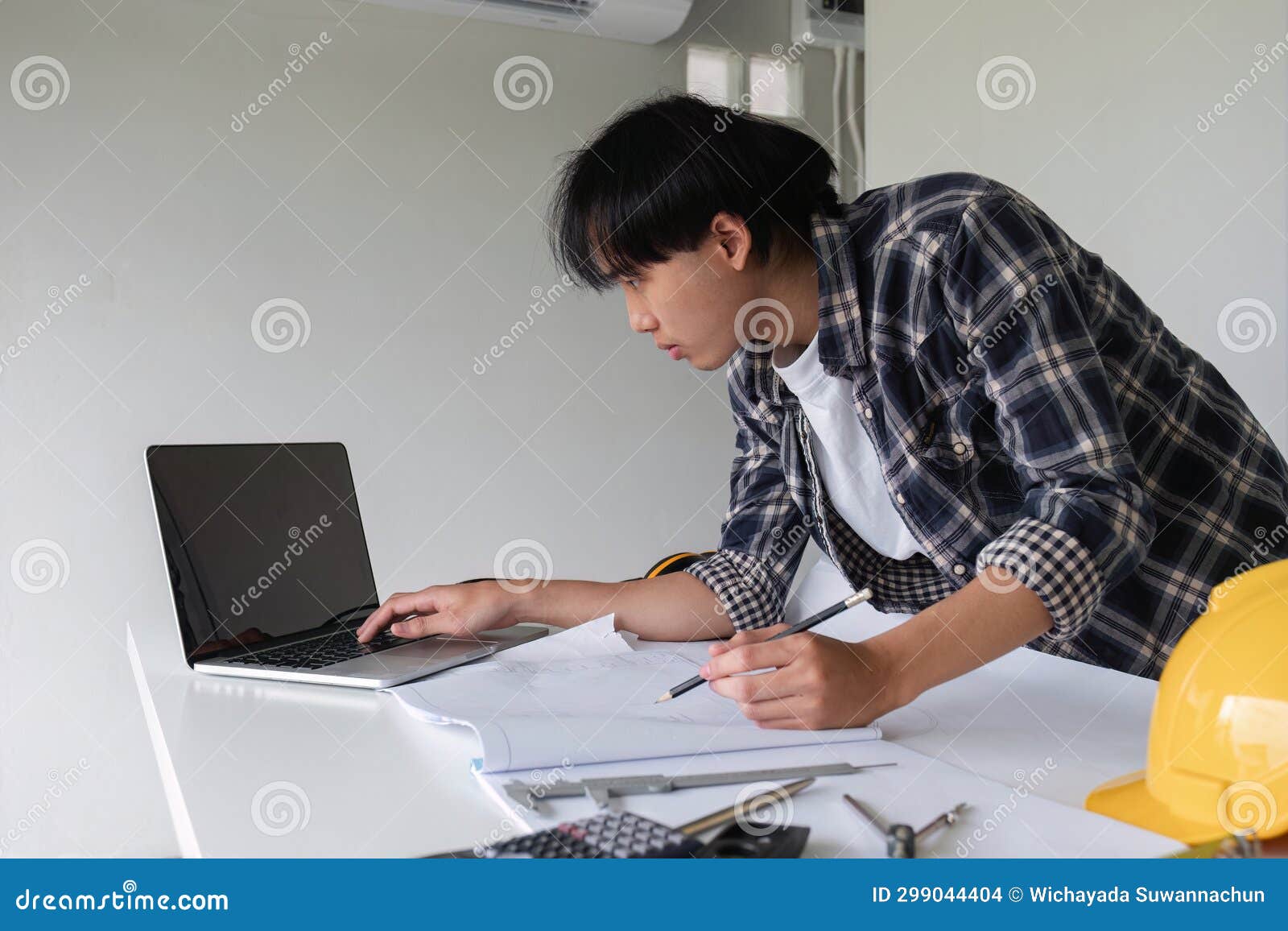 Young Asian Engineer Drawing Construction Project Plans on Plan Paper ...