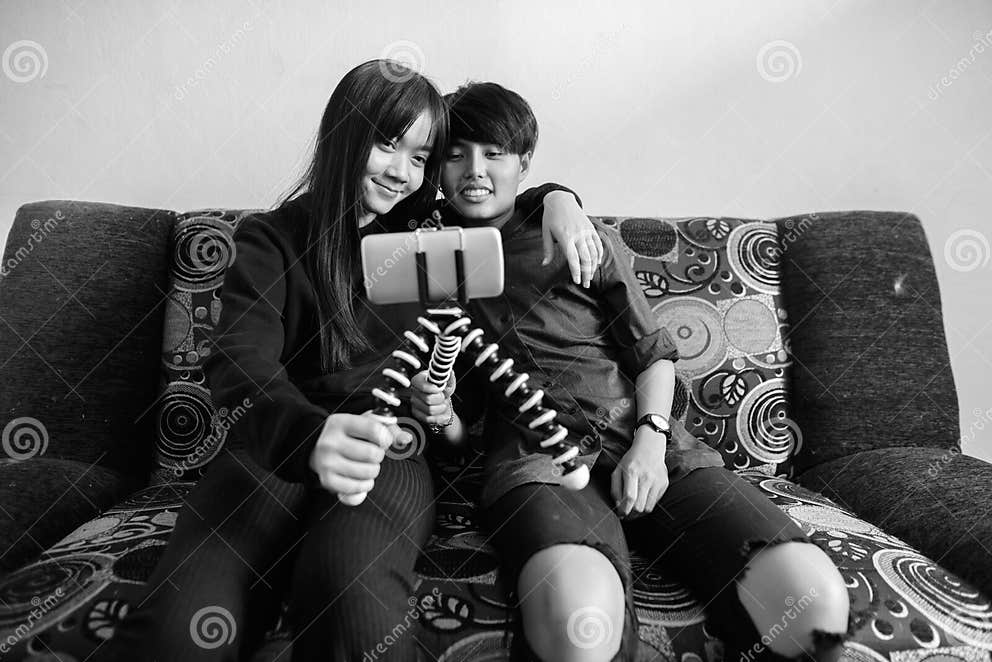 Young Asian Lesbian Couple Sitting On The Sofa Together And In Love