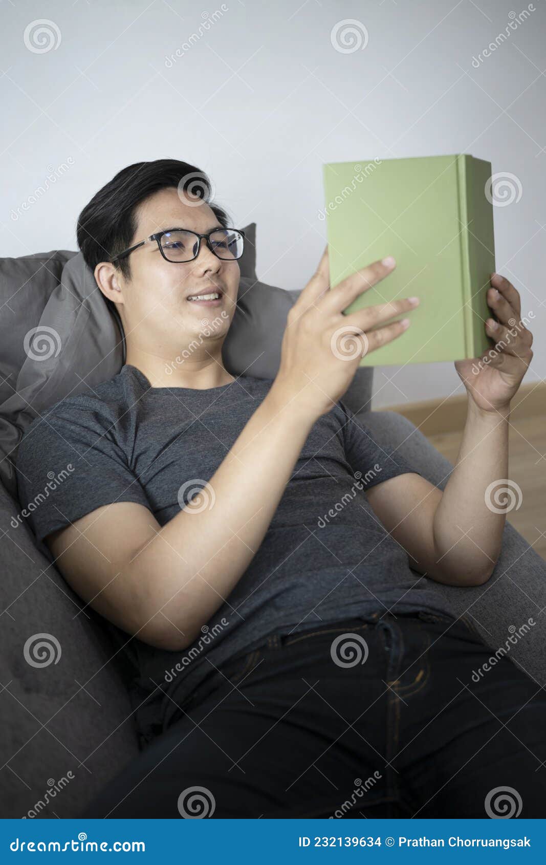 Young Asian Man Reading Book on Sofa. Stock Photo - Image of home, book ...
