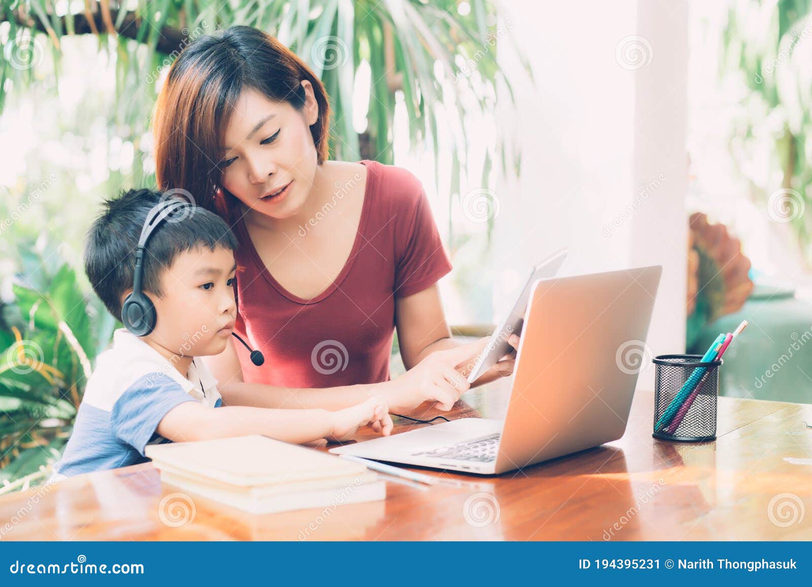 Young Asian Mother and Son Using Laptop Computer and Tablet for Study ...