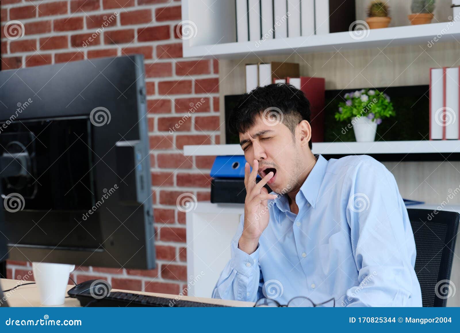 Young Asian Office Man Yawning while Working on Paperwork and Computer ...