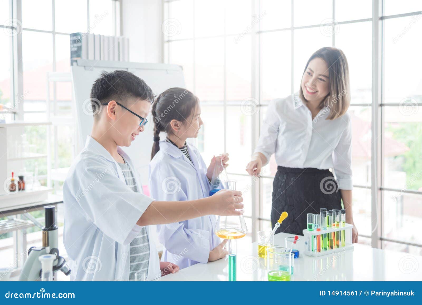 Student Doing Experiment with Their Teacher in Chemistry Classroom ...