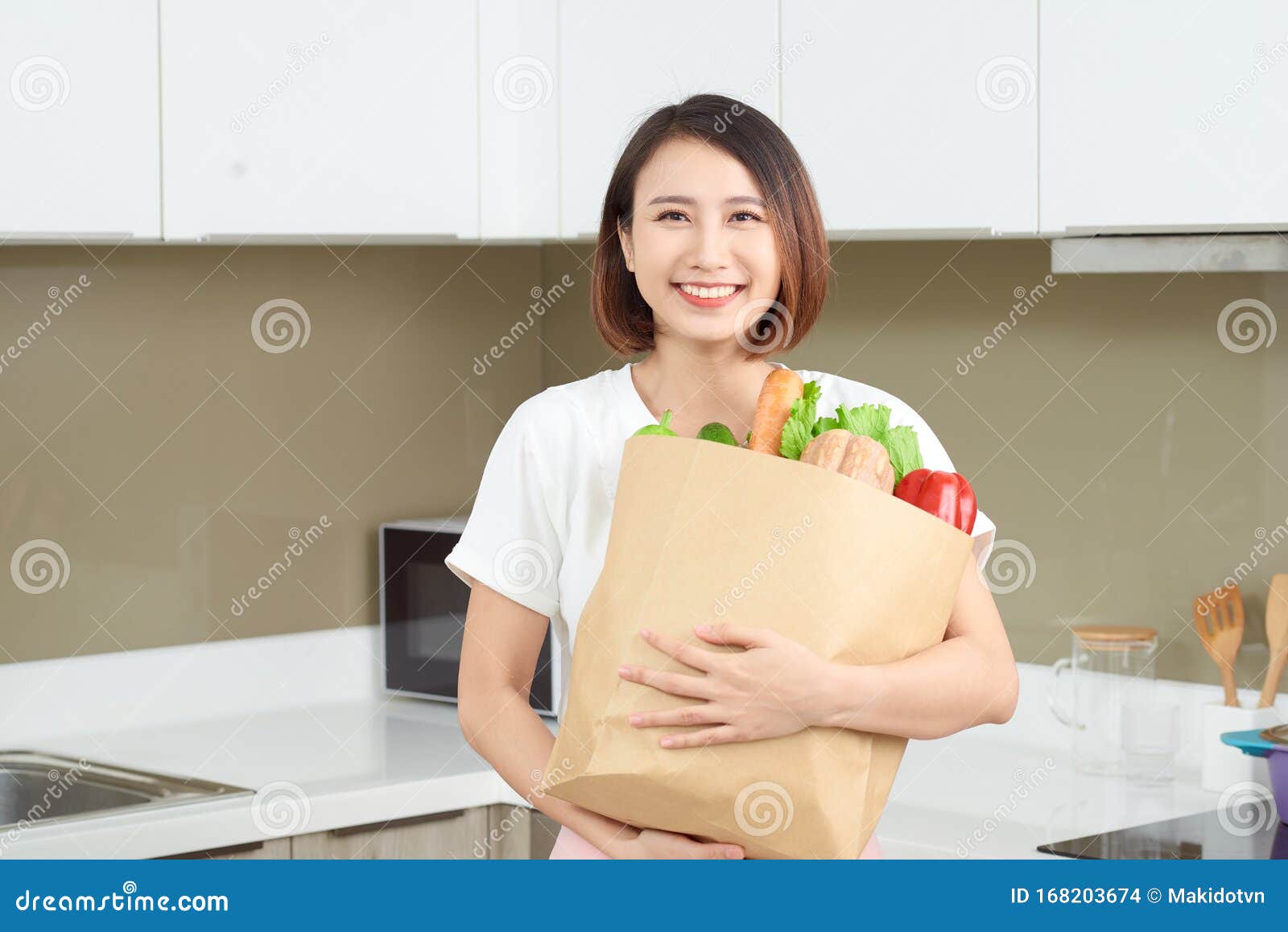 Young Asian Woman Holding Grocery Shopping Bag with Vegetables in the ... Young Asian Woman Holding Grocery Shopping Bag with Vegetables in the ...
