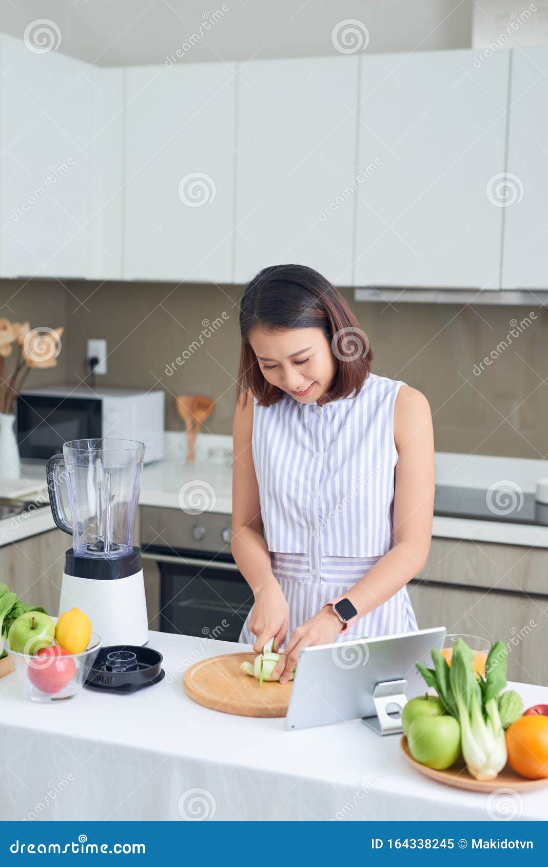 Young Asian Woman Making Smoothies From Recipe In Tablet Stock Image