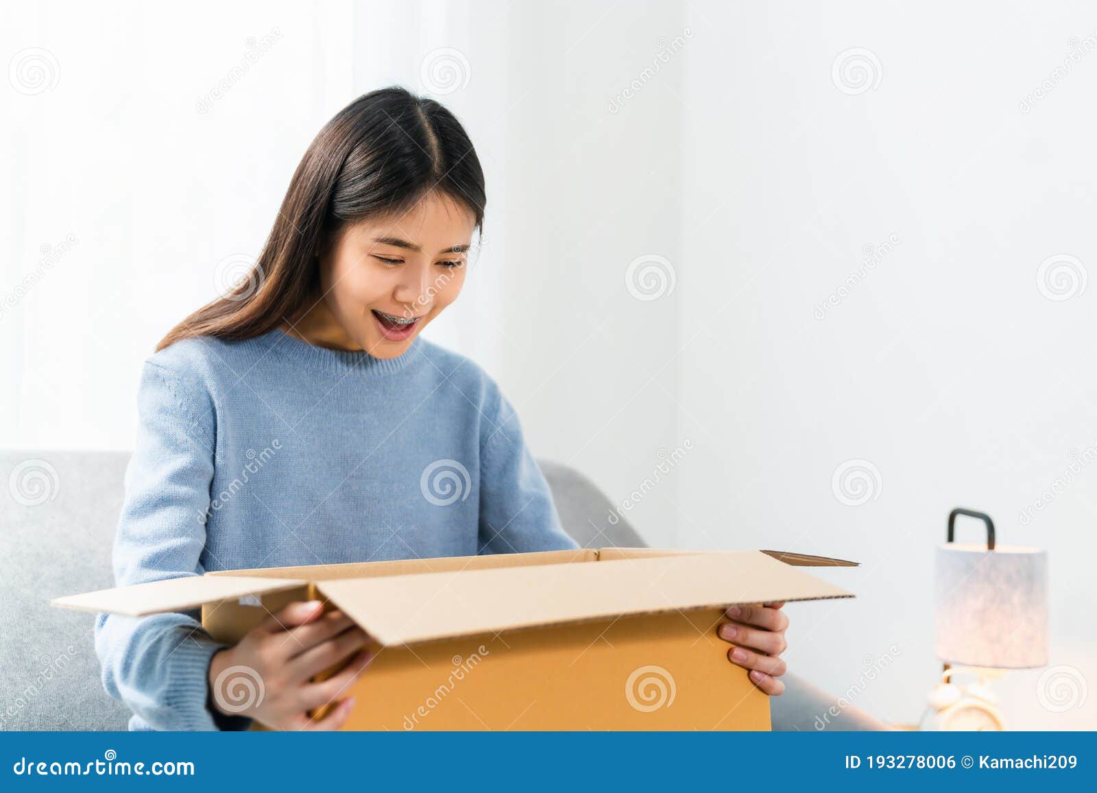 Young Asian Woman Open Box Parcel while Sitting on Sofa. Stock Photo ...