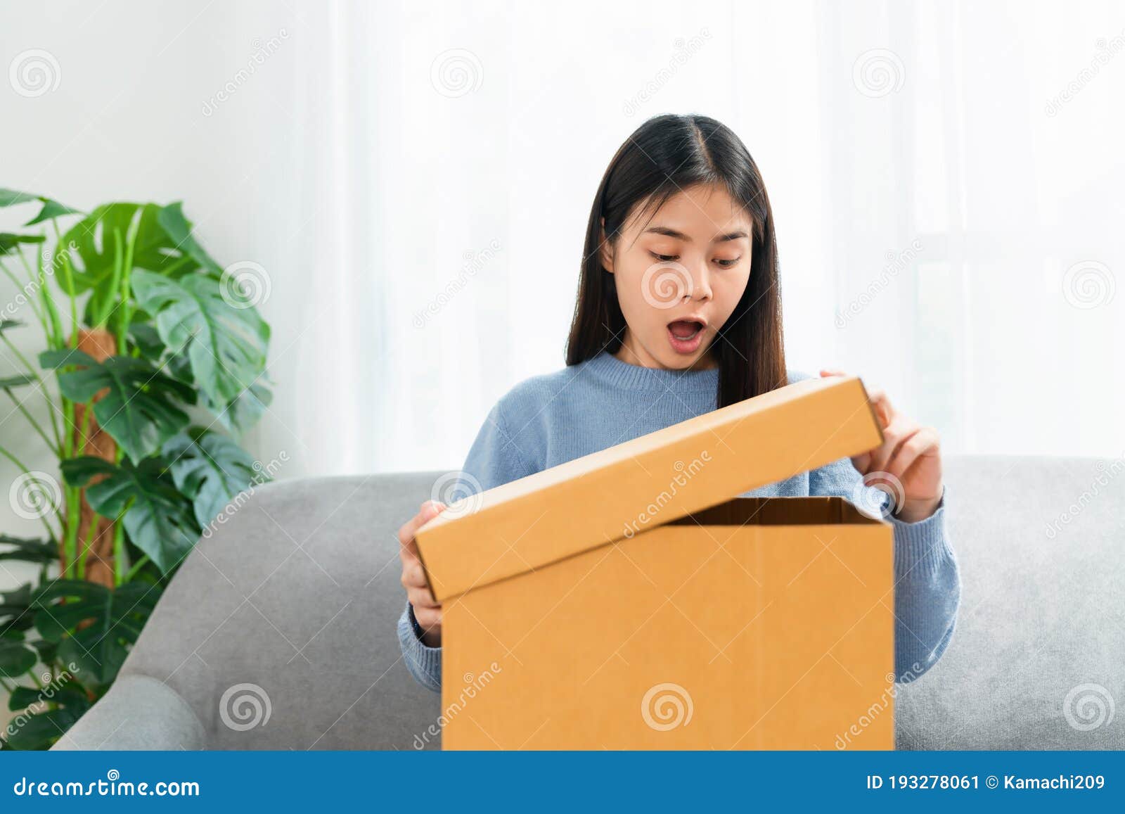 Young Asian Woman Open Box Parcel while Sitting on Sofa. Stock Image ...