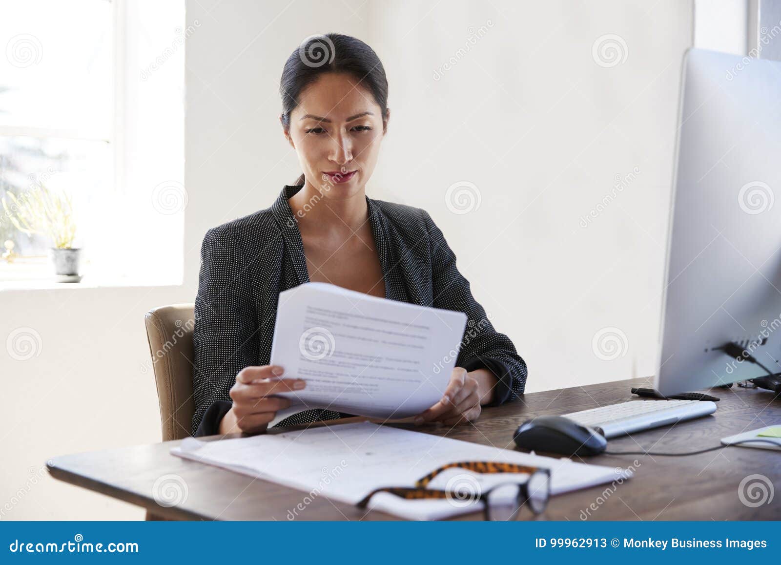 Young Asian Woman Reading Documents at Her Desk in an Office Stock ...