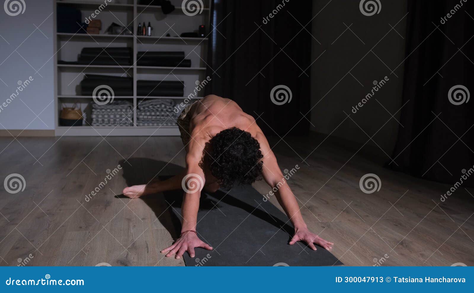 A Young and Athletic Man with a Bare Torso Does Yoga and Exercises ...