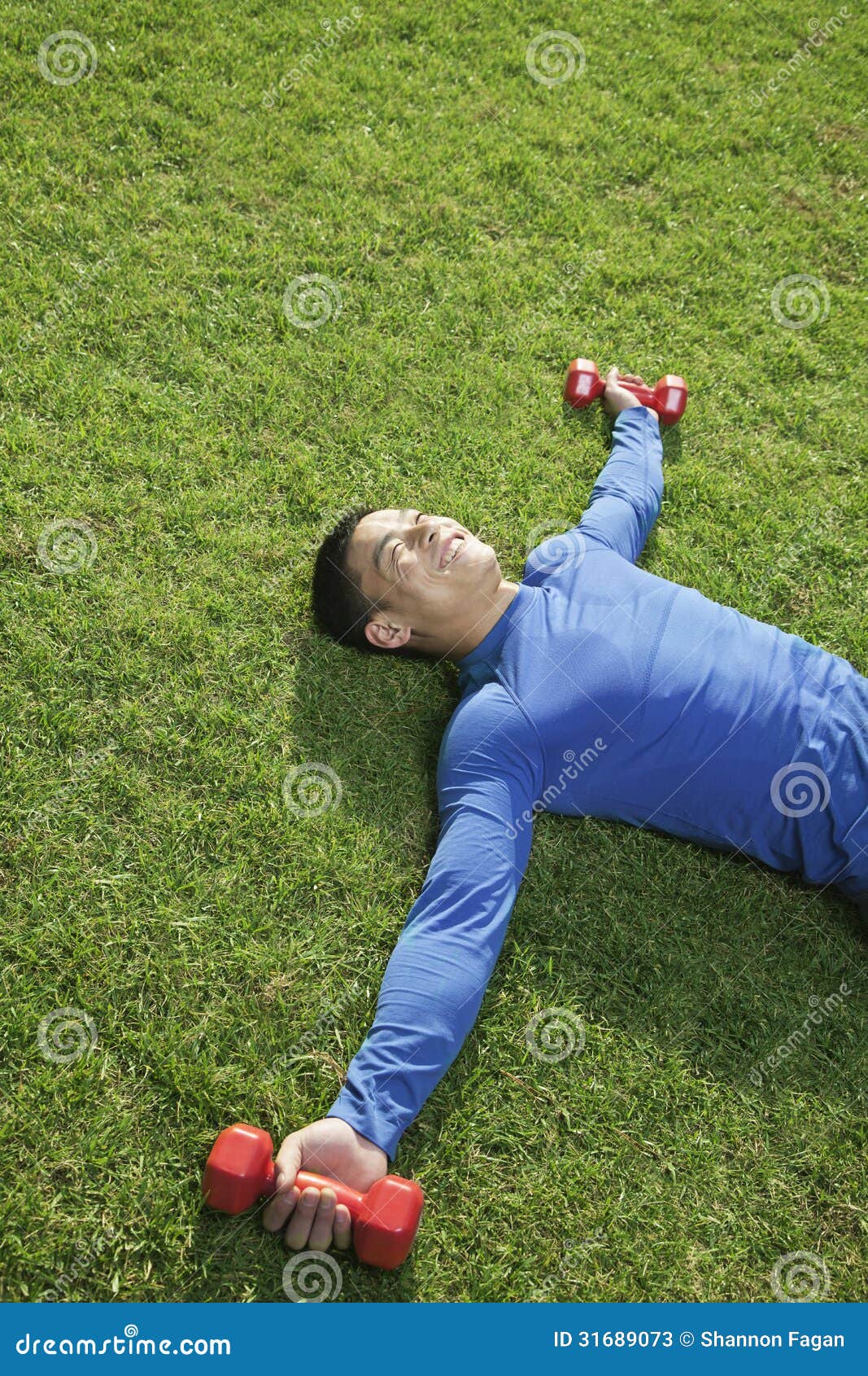 Young Athletic Man Lying Down in Park with Dumbbells in Grass Stock ...