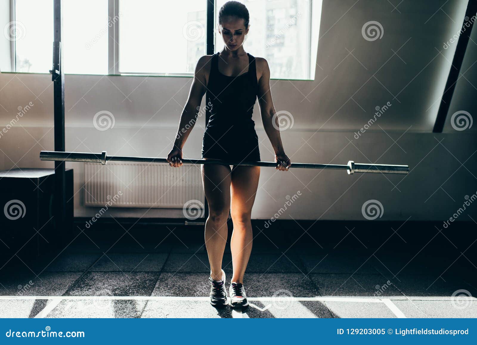Young Athletic Sportswoman Practicing Lifting a Barbell without Weights ...