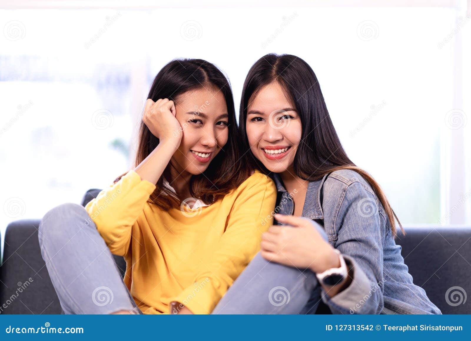Young Attractive Asian Girlfriends Sitting Together At Couch Sofa At