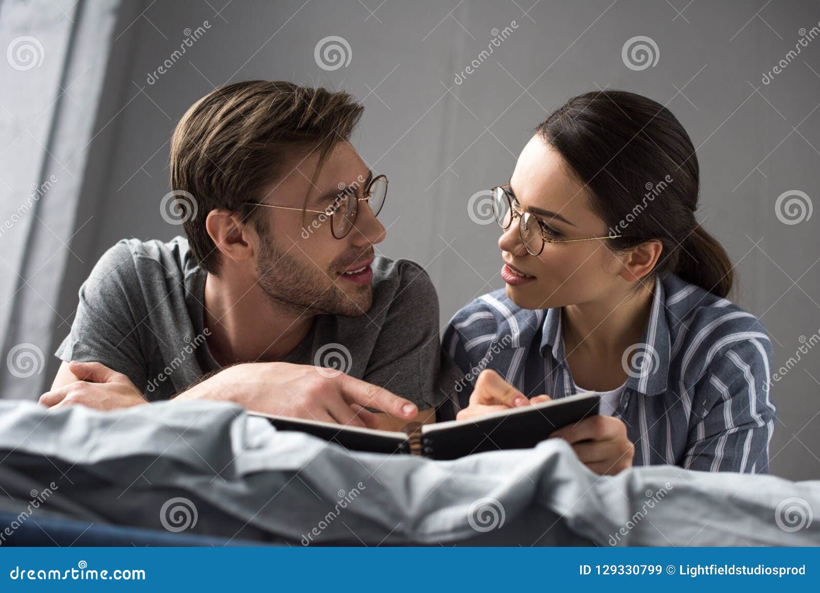 Young Attractive Couple Writing in Notepad while Lying Stock Image ...