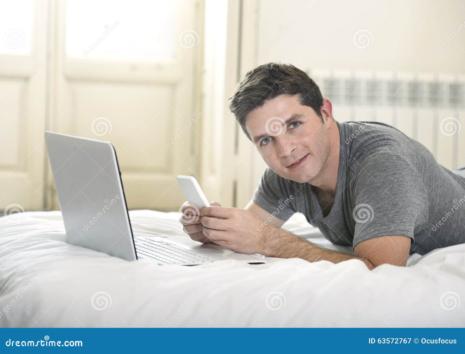 Young Attractive Man Lying on Bed or Couch Using Mobile Phone and ...