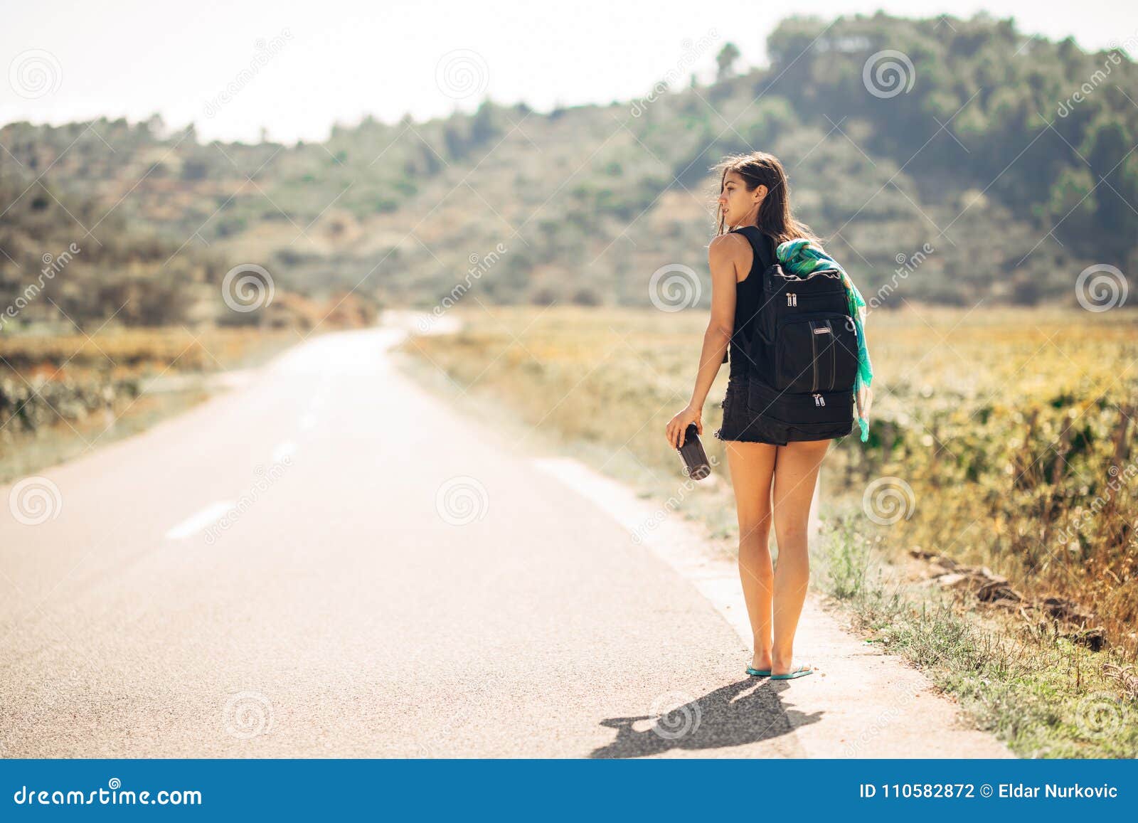 Young Backpacking Adventurous Woman Hitchhiking On The Road Traveling