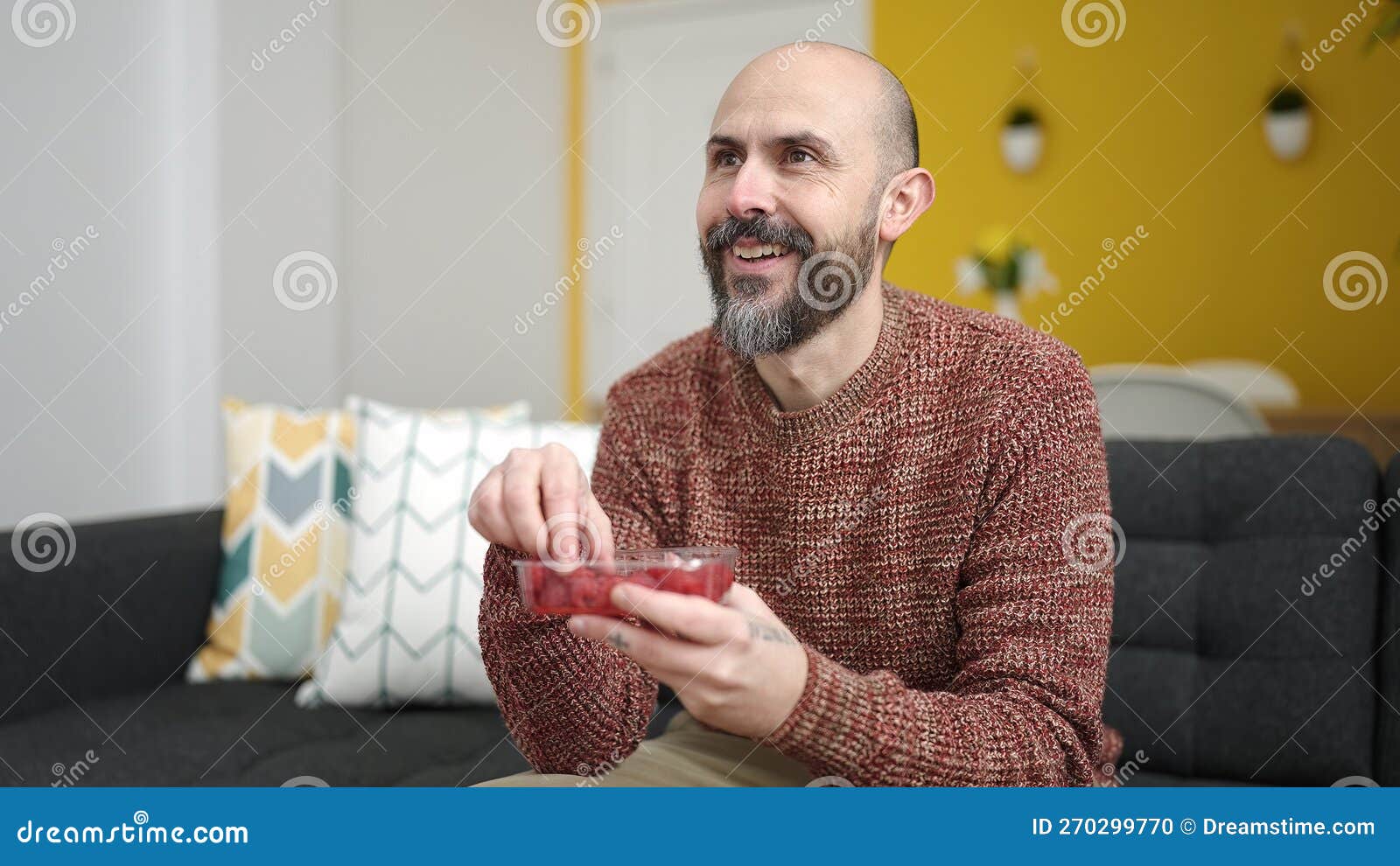 Young Bald Man Eating Raspberries Sitting on Sofa at Home Stock Photo ...