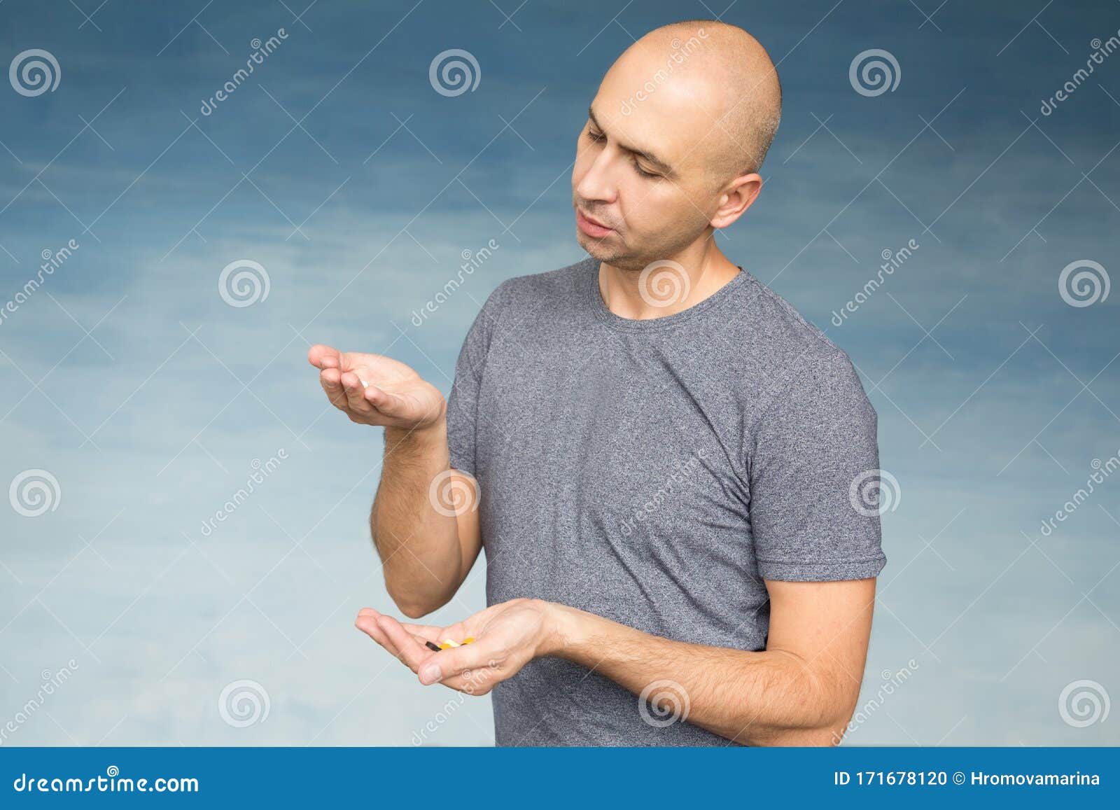 A Young Bald Man Eats Pills on a Blue Background. Stock Photo - Image ...
