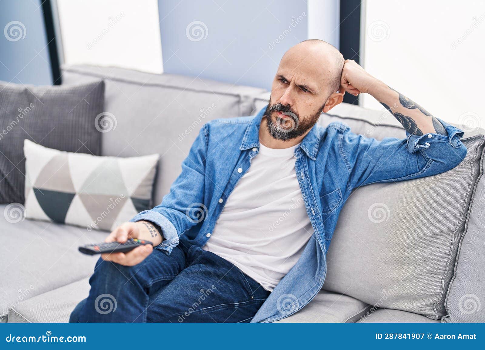 Young Bald Man Watching Tv Sitting on Sofa with Boring Expression at ...