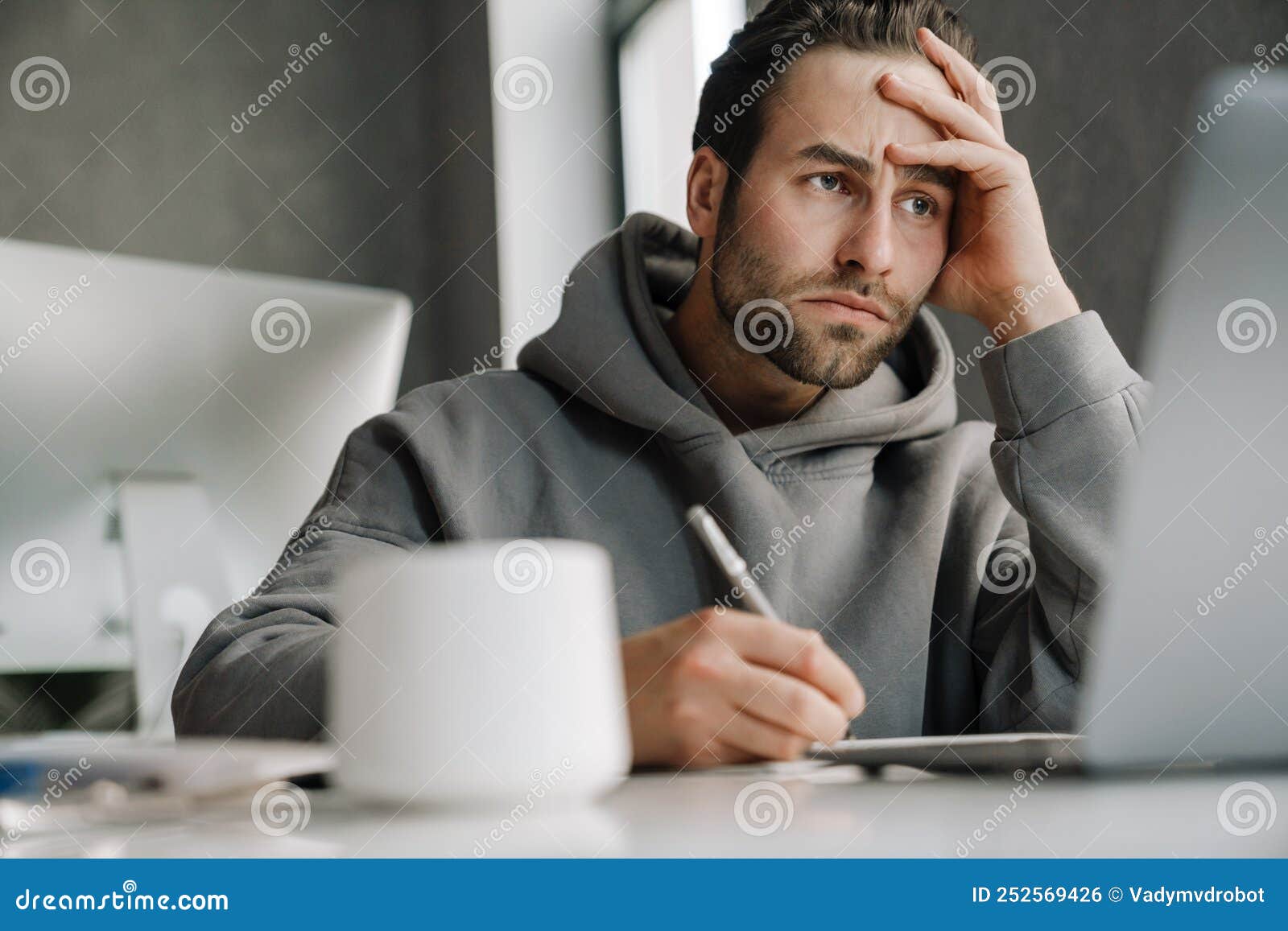 Young Beard Man Working with Laptop while Writing Down Notes Stock ...