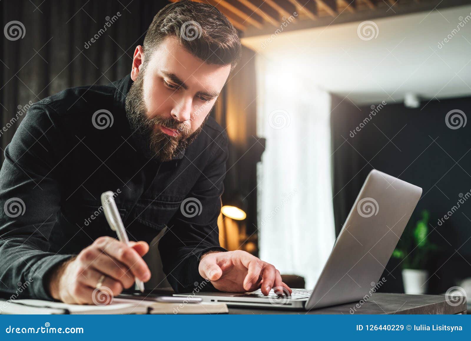 Businessman is Standing Near Computer, Working on Laptop, Making Notes ...