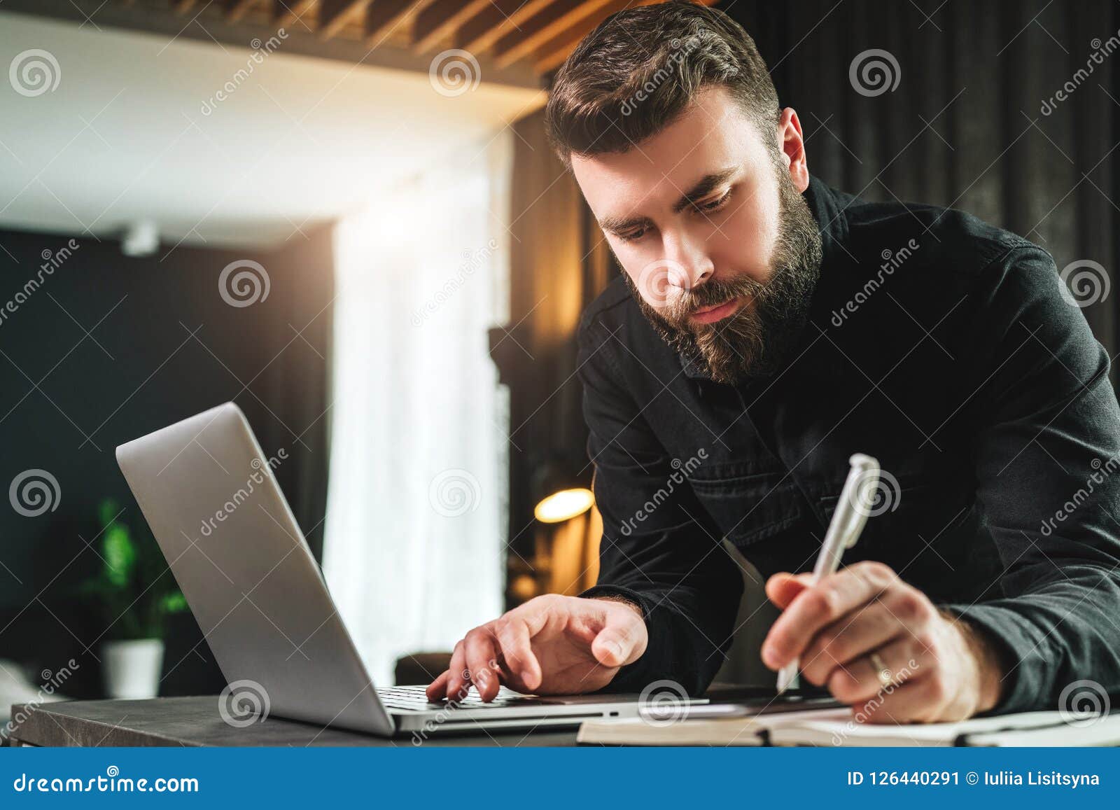 Businessman is Standing Near Computer, Working on Laptop, Making Notes ...