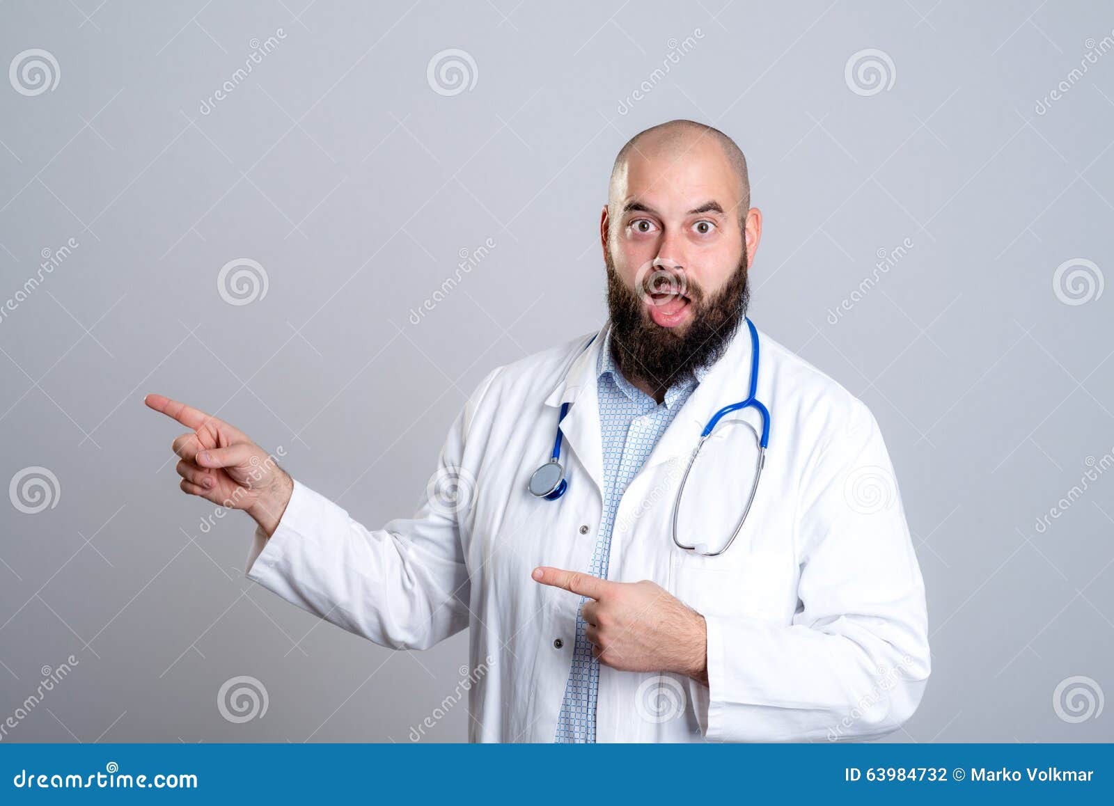 Young Bearded Doctor Looking Amazed and Pointing To Side Stock Photo ...