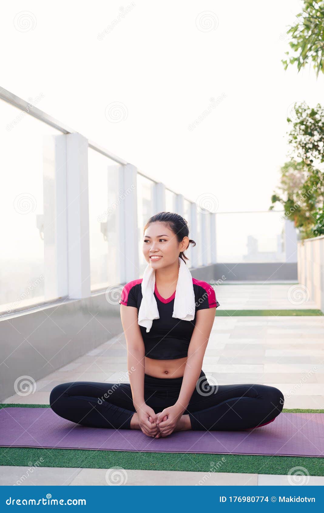 Young Beautiful Asian Woman Sitting On Yoga Mat And Smiling In Morning