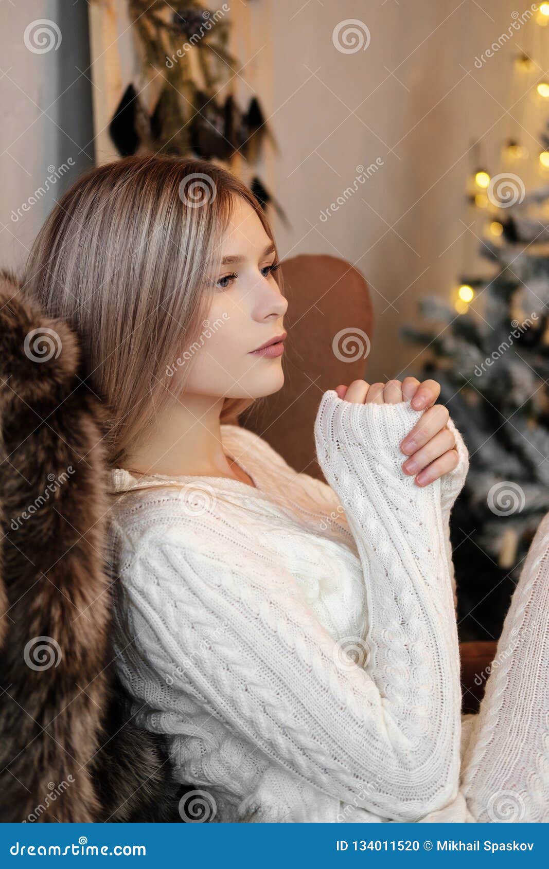 Young Beautiful Blonde Girl In A Warm White Knitted Sweater On The