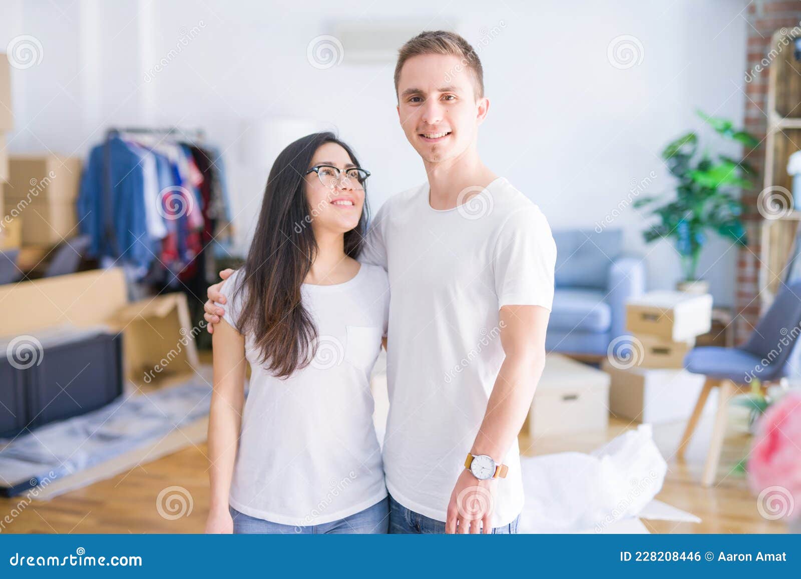 Young Beautiful Couple Standing At New Home Around Cardboard Boxes