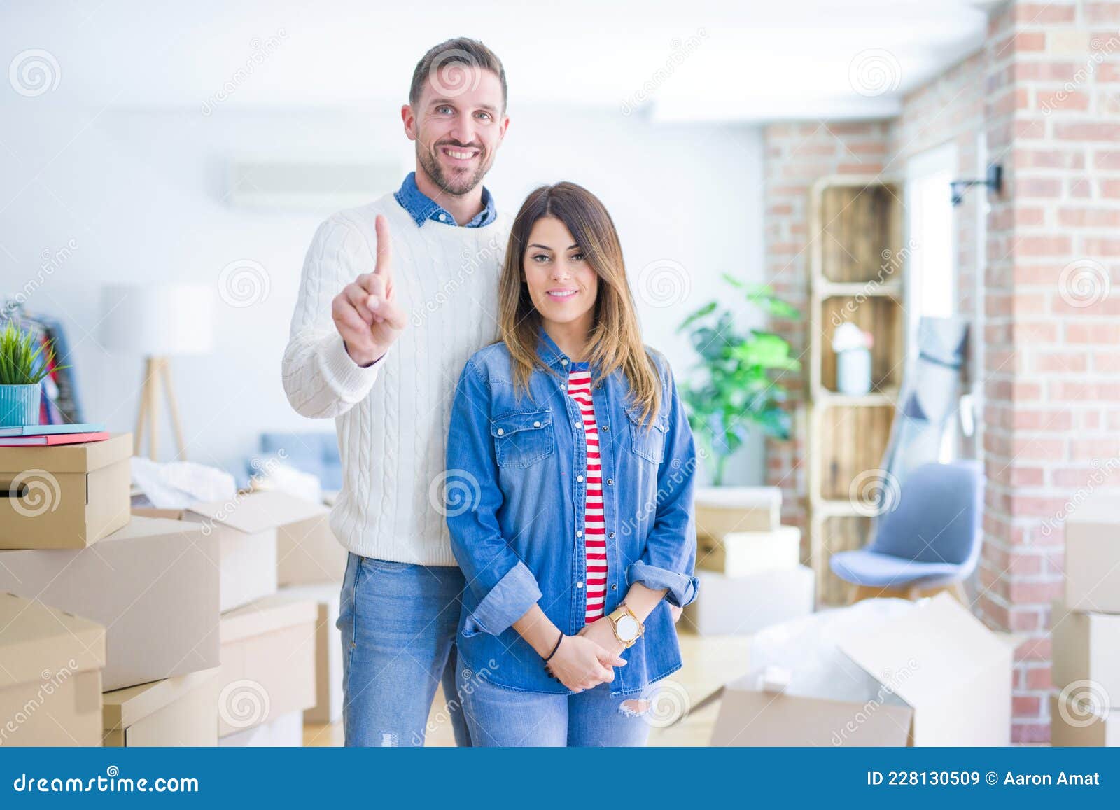 Young Beautiful Couple Standing At New Home Around Cardboard Boxes