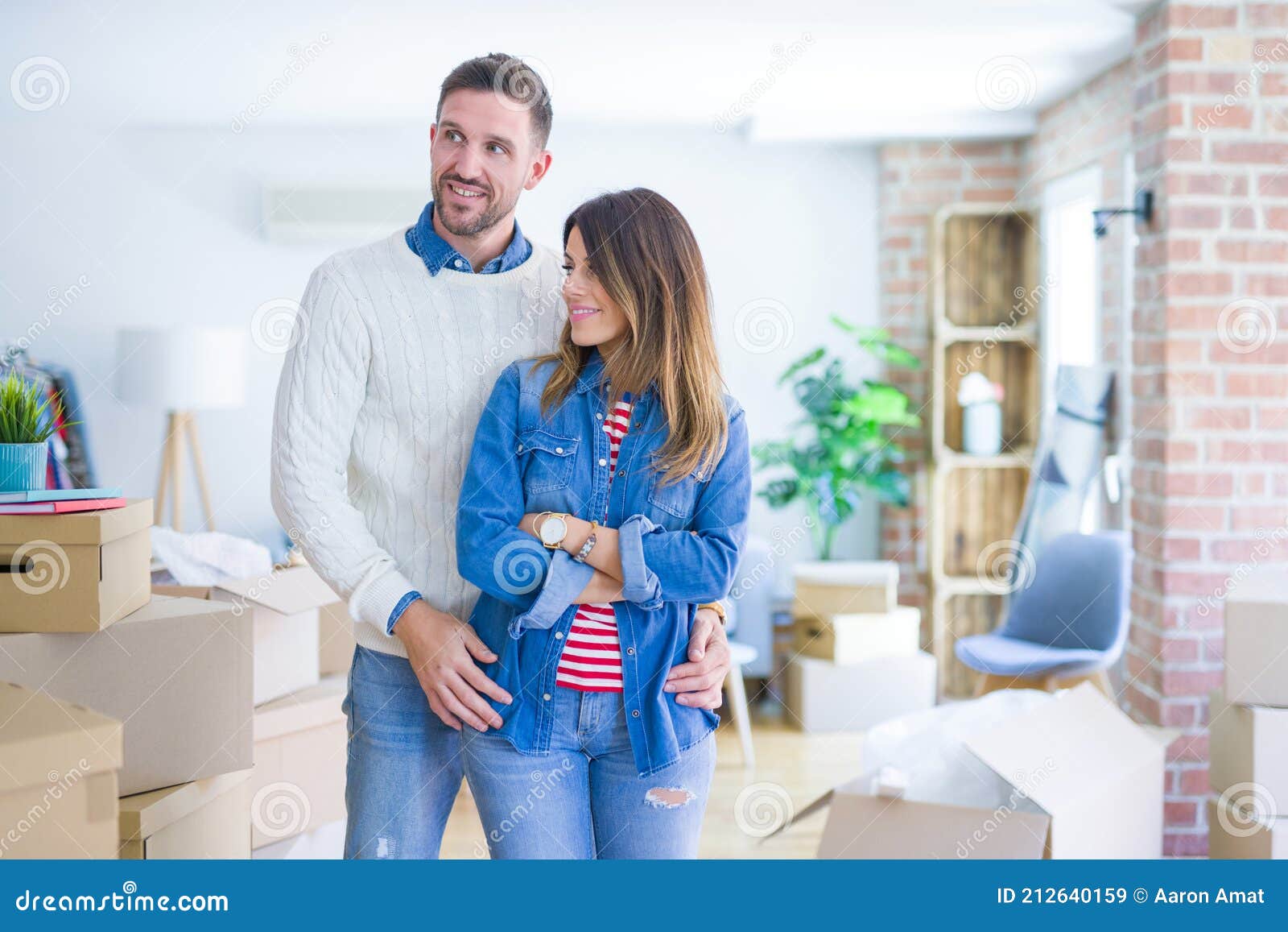 Young Beautiful Couple Standing At New Home Around Cardboard Boxes