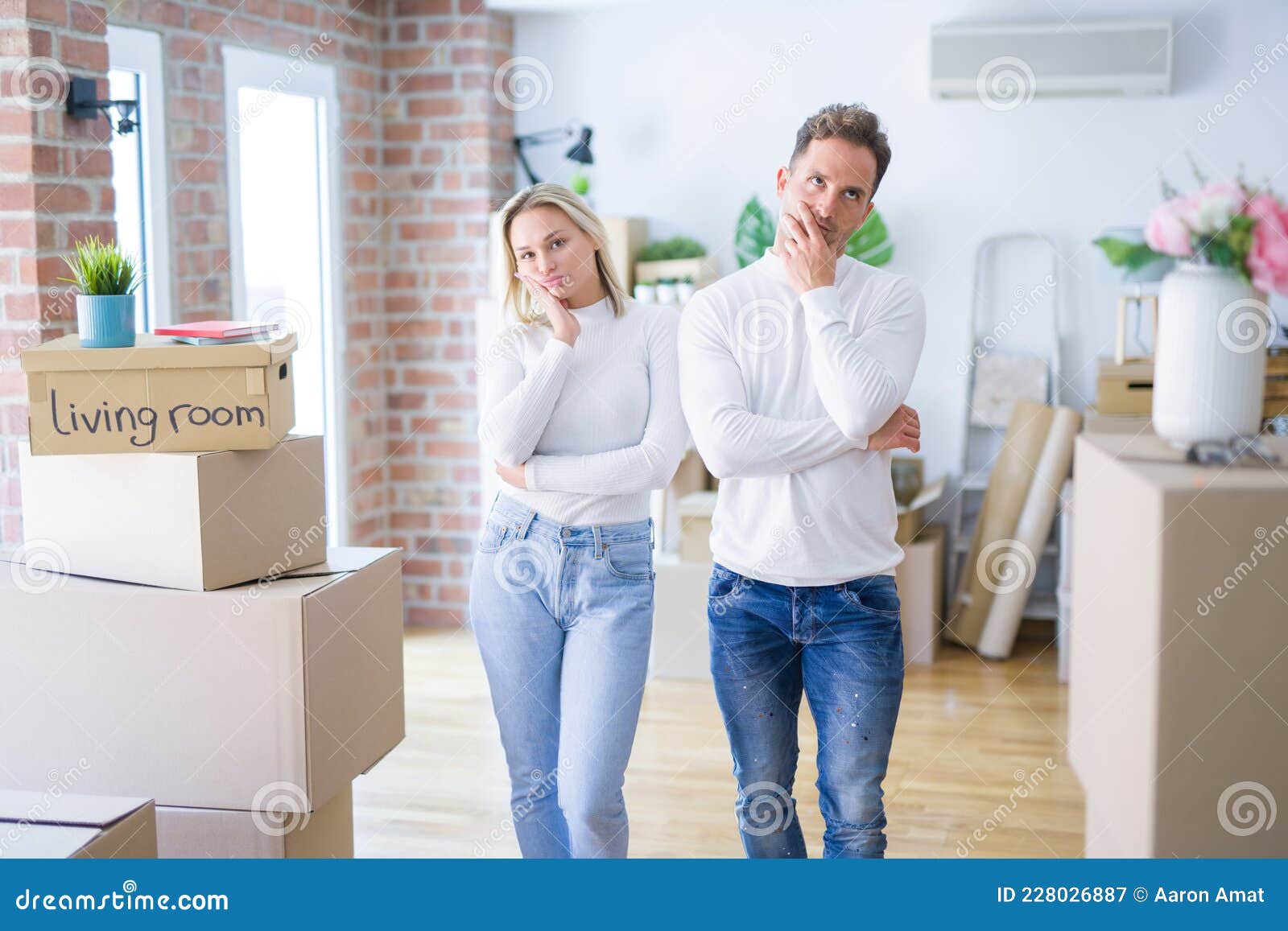 Young Beautiful Couple Standing At New Home Around Cardboard Boxes