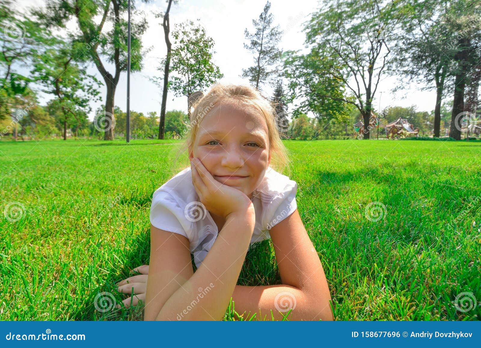A Young And Beautiful Girl Lies On The Green Grass In The Park And
