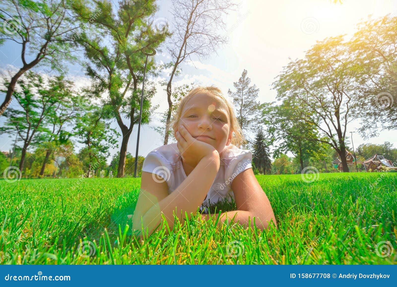 A Young And Beautiful Girl Lies On The Green Grass In The Park And