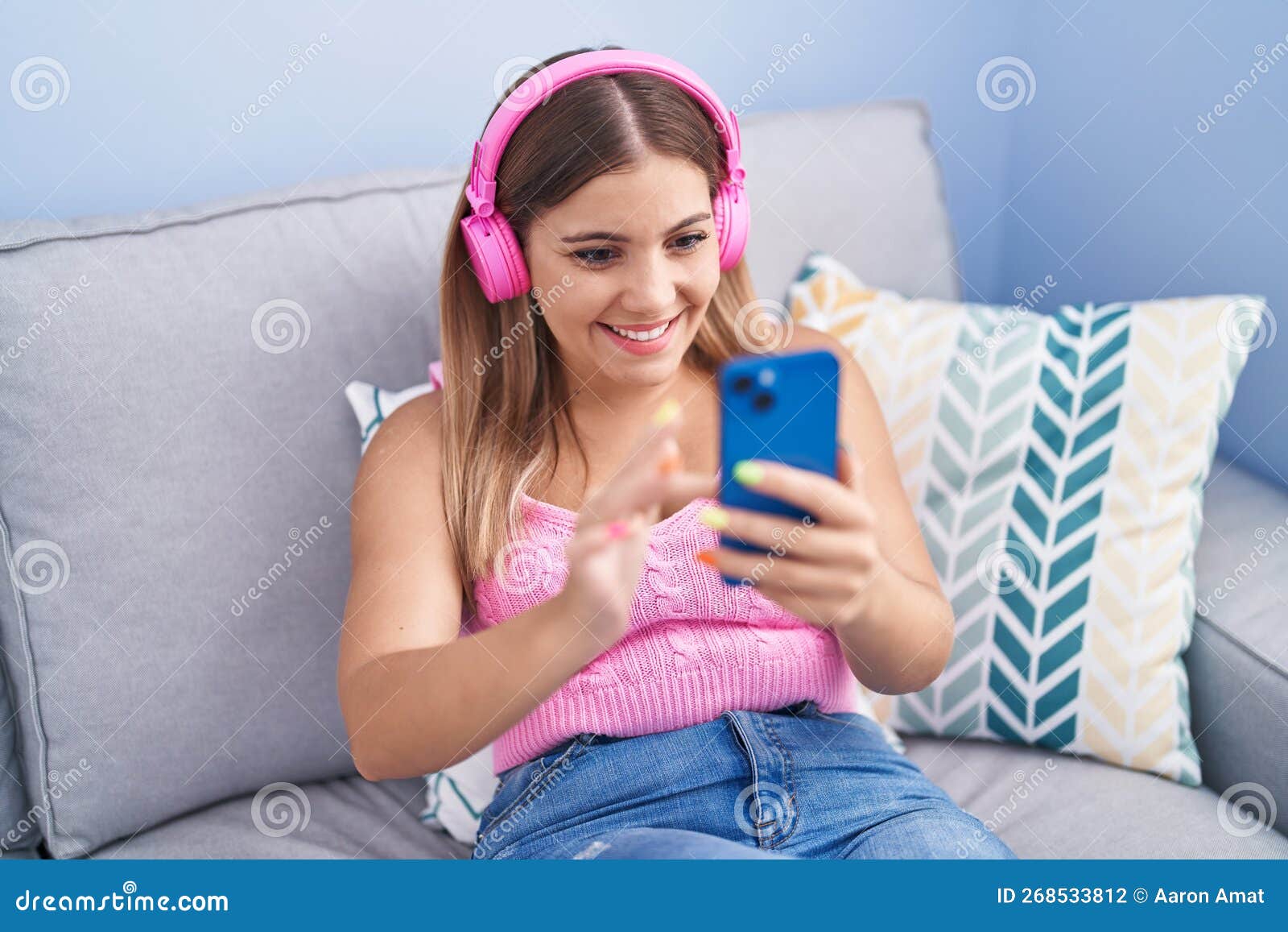 Young Beautiful Hispanic Woman Listening To Music Sitting On Sofa At