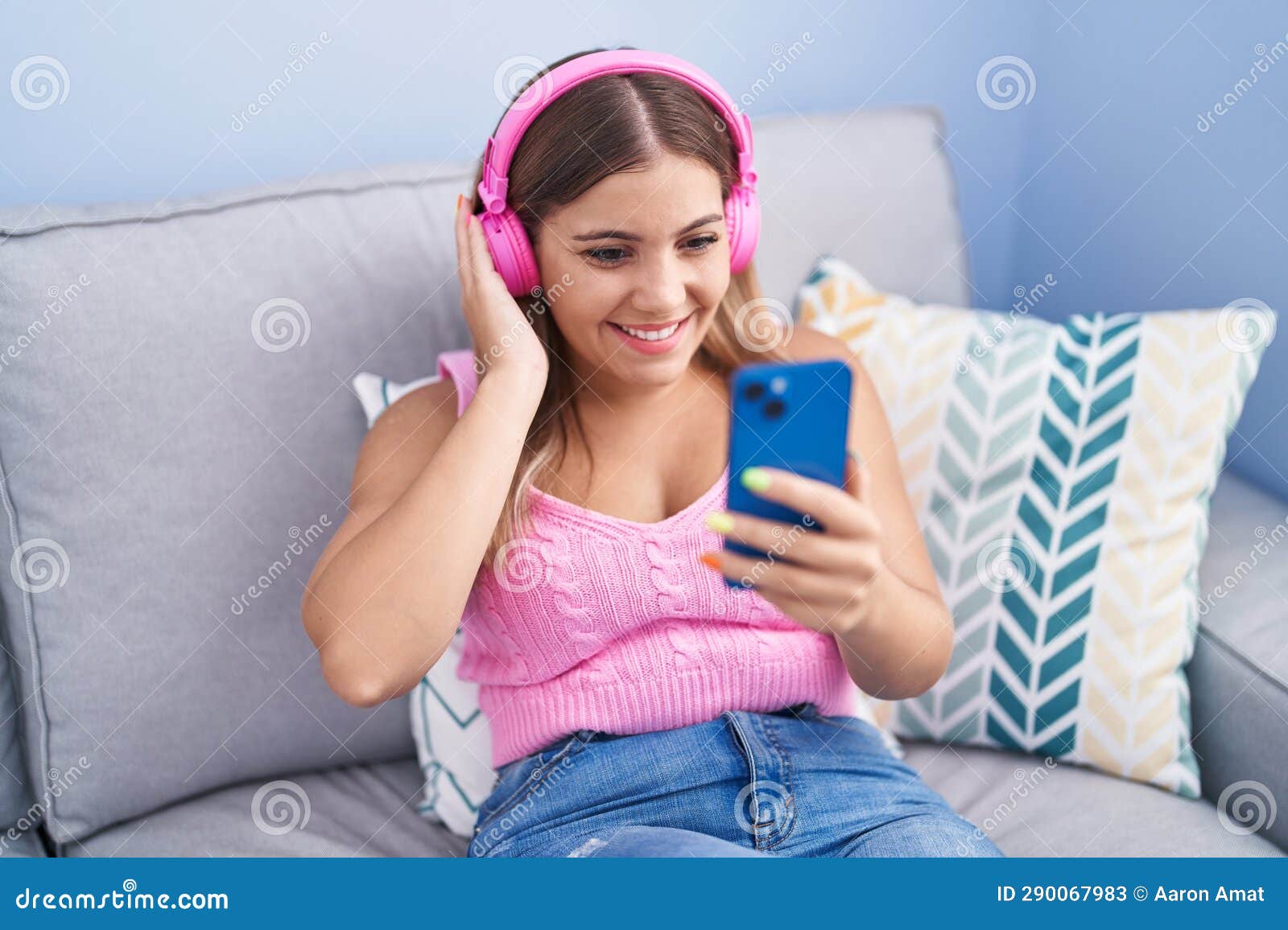 Young Beautiful Hispanic Woman Listening To Music Sitting On Sofa At