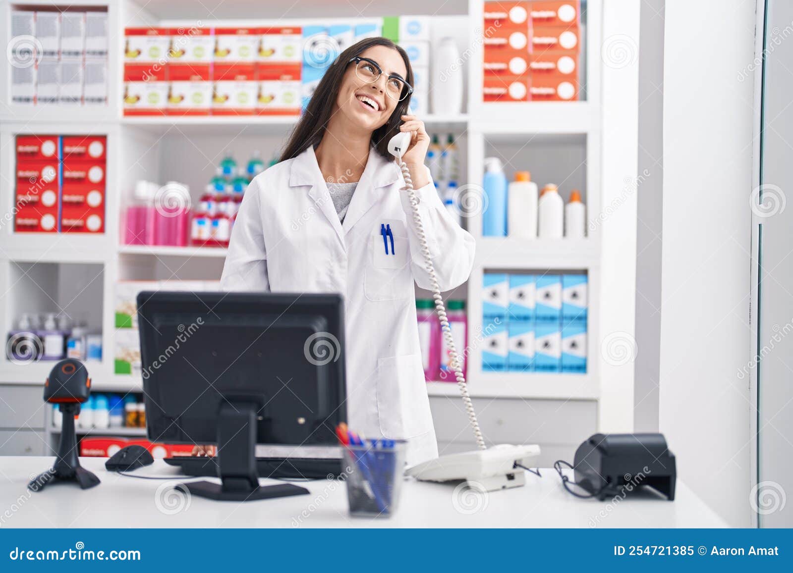 Young Beautiful Hispanic Woman Pharmacist Talking on Telephone Using ...