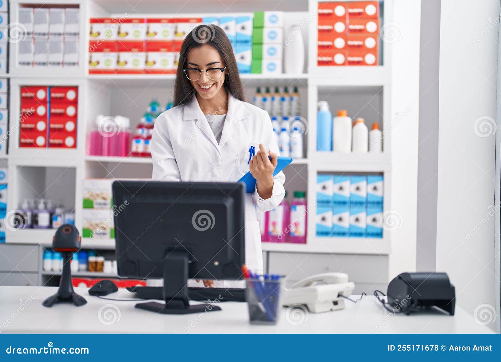 Young Beautiful Hispanic Woman Pharmacist Using Touchpad and Computer ...
