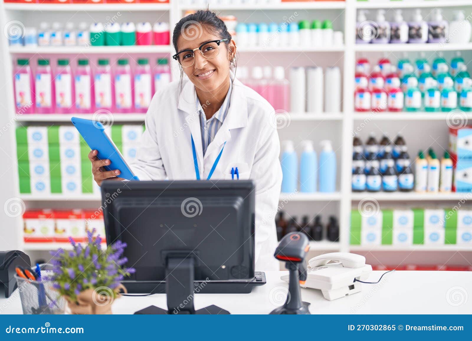 Young Beautiful Hispanic Woman Pharmacist Using Touchpad and Computer ...