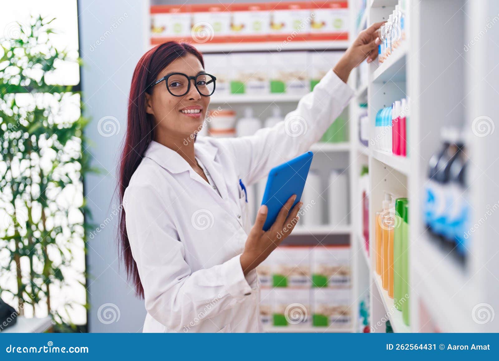 Young Beautiful Hispanic Woman Pharmacist Using Touchpad Working at ...