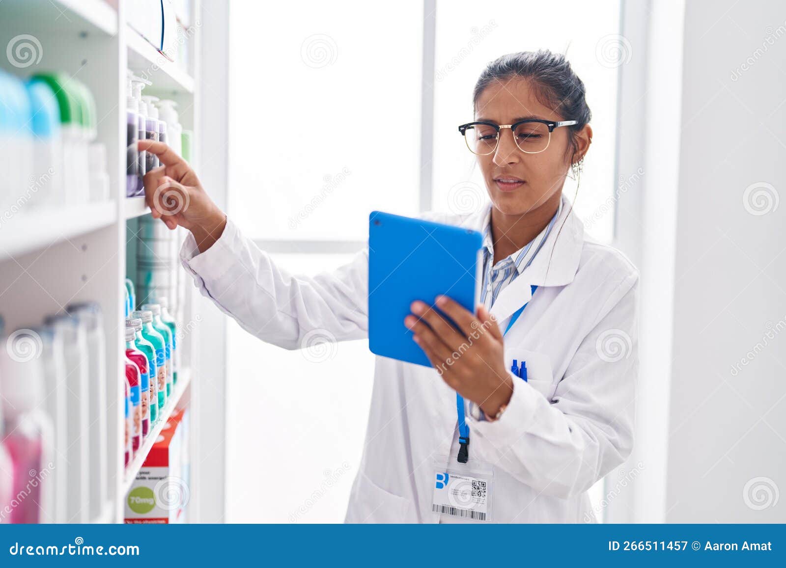 Young Beautiful Hispanic Woman Pharmacist Using Touchpad Working at ...