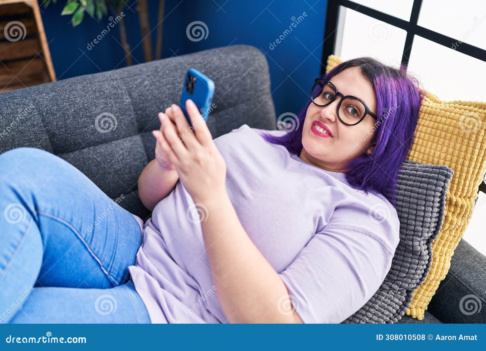 Young Beautiful Plus Size Woman Using Smartphone Lying on Sofa at Home ...