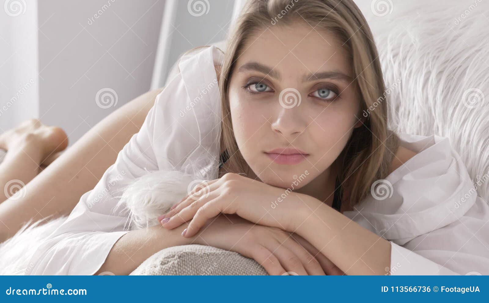Young Beautiful Caucasian Woman Lying On Sofa In White Shirt Looking At