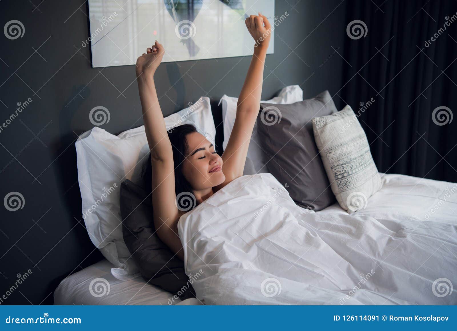 Young Beautiful Smiling And Brunette Woman Lying In Bed Trying To Wake