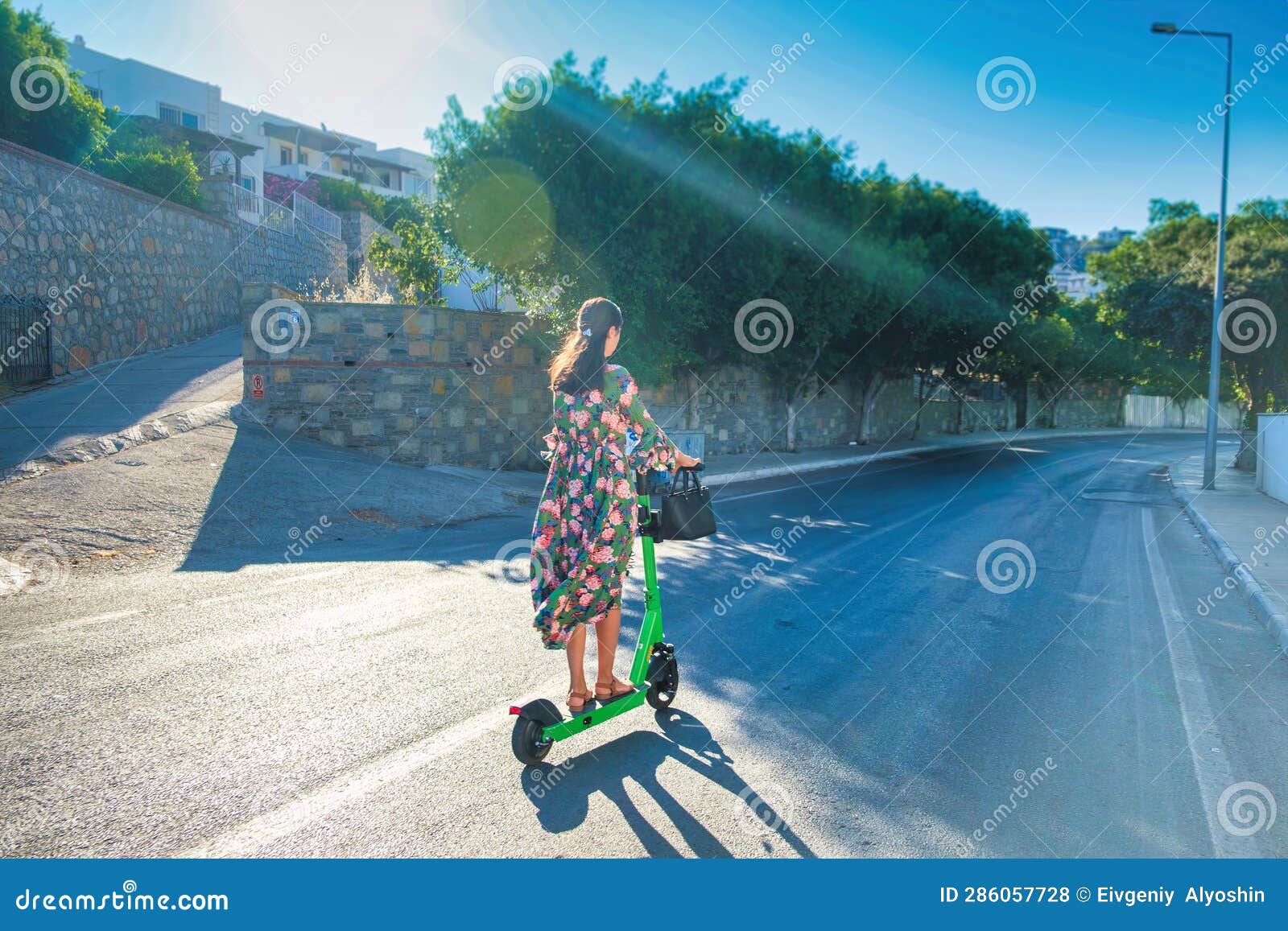 Young Beautiful Woman In Dress Rides An Electric Scooter On Empty